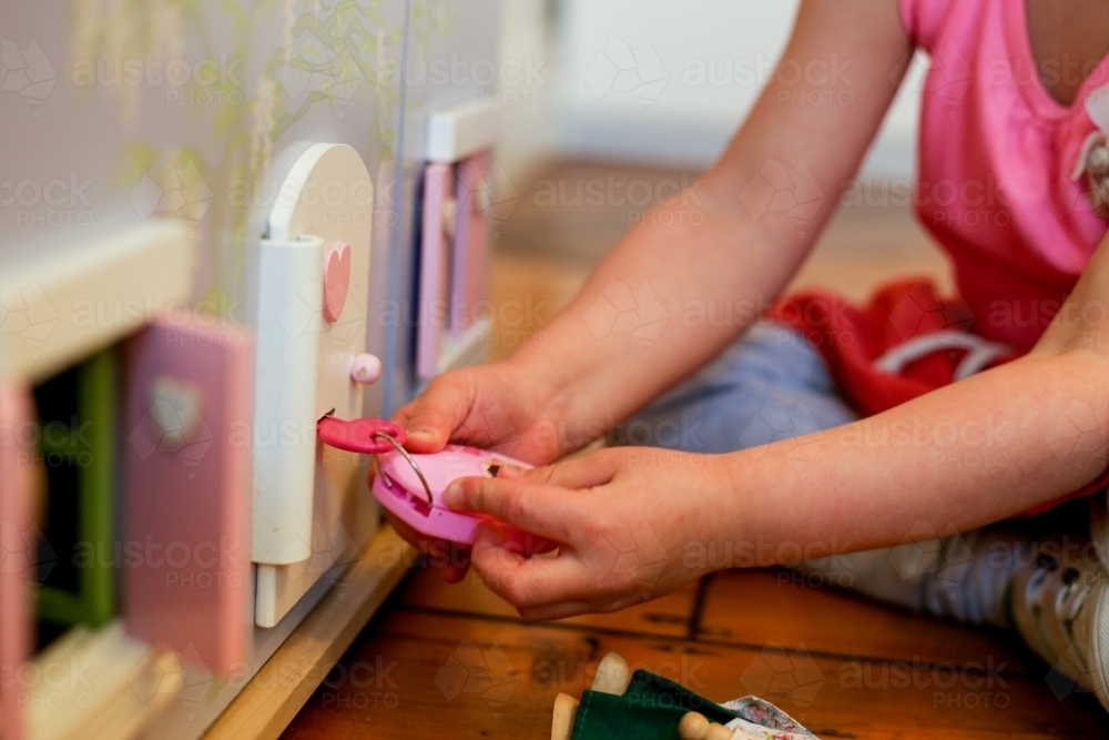 Image of Young girl playing with toy keys and a dollhouse - Austockphoto
