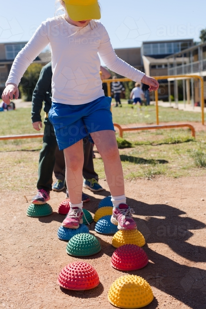 Image of Young girl stepping on colourful stepping stones - Austockphoto