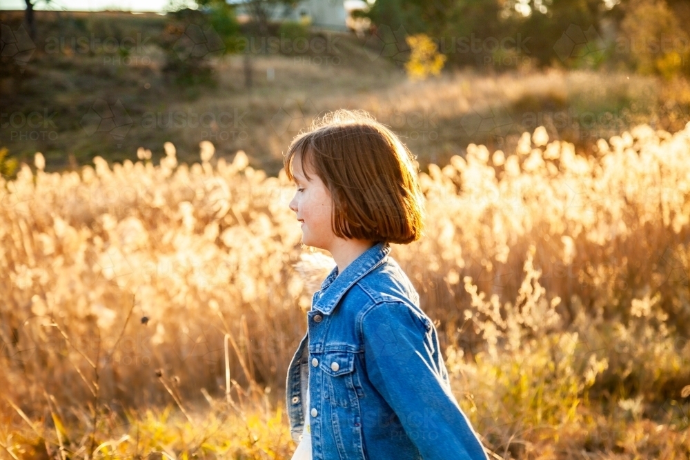 Image of Young girl twirling around outside backlit by golden light ...