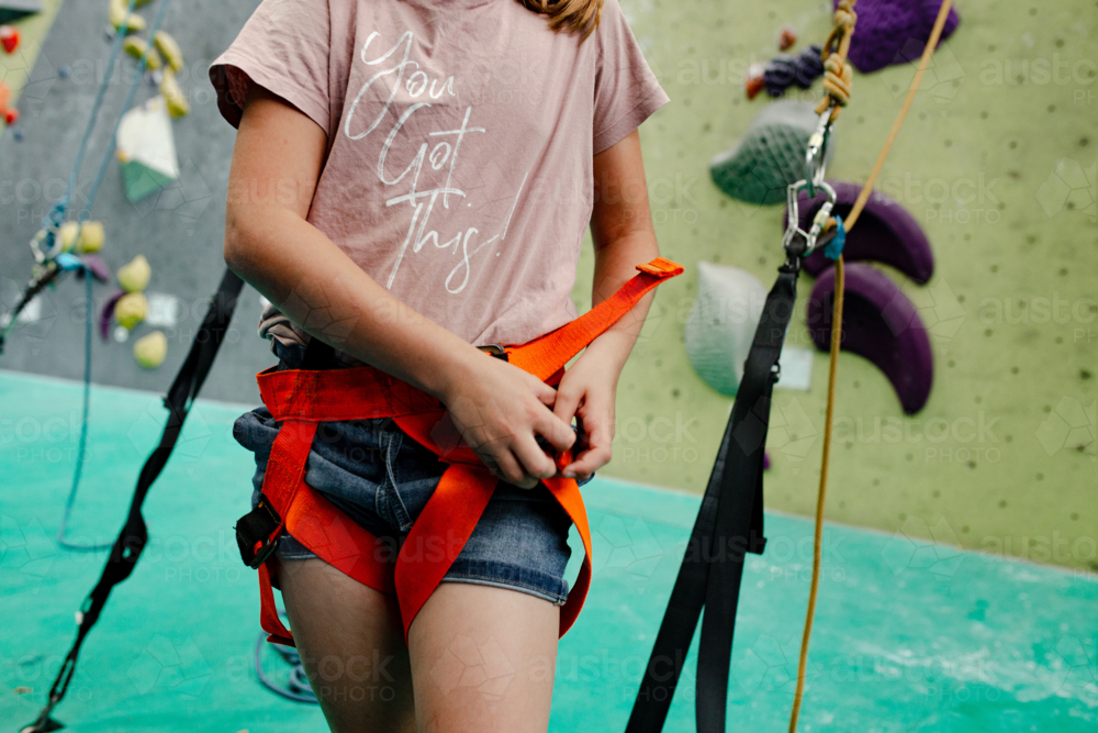 Image of Young girl wearing her harness in a rock climbing gym ...