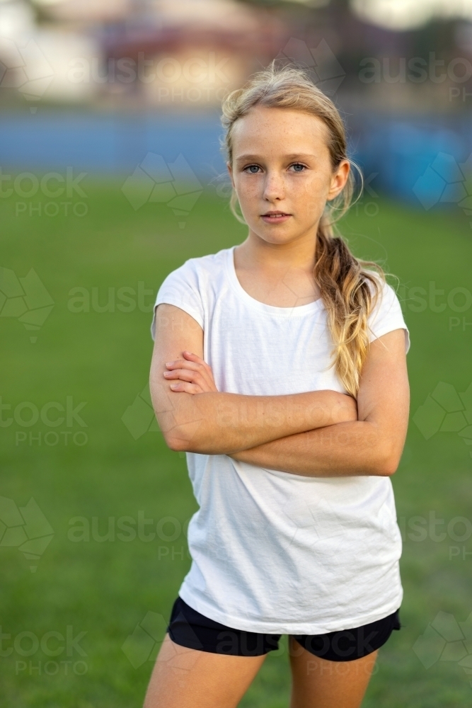 Image Of Young Girl Wearing White Tee Shirt And Black Shorts Standing With Arms Crossed Looking
