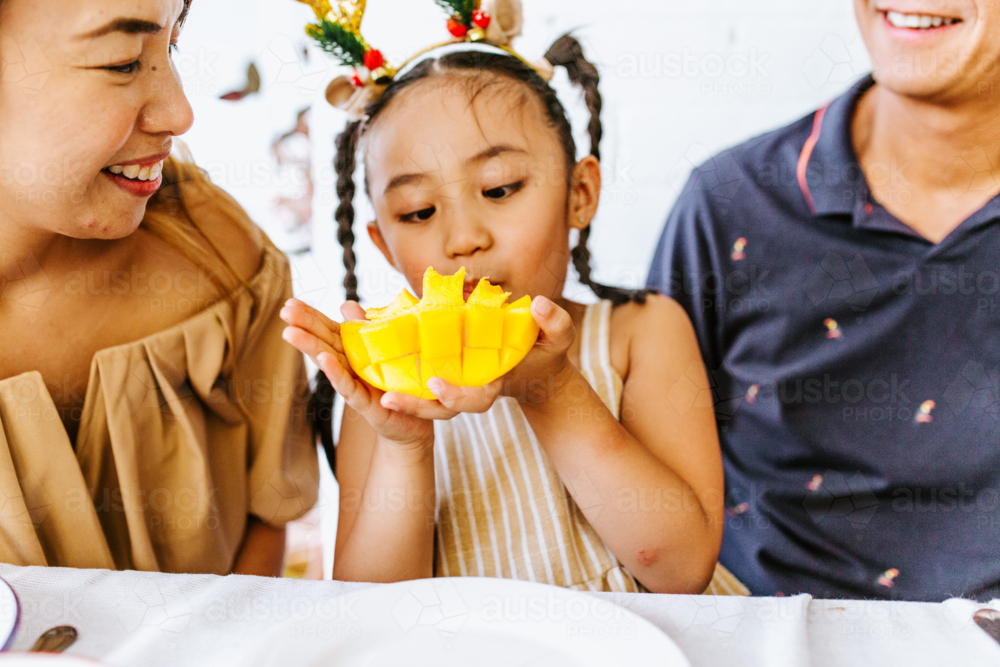 Image of Young girl with Christmas headdress enjoying ripe mango ...