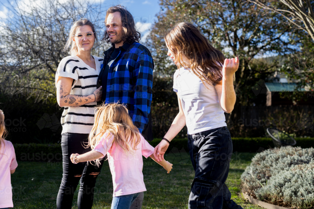 Image of Young girls running around mum and dad in the garden ...