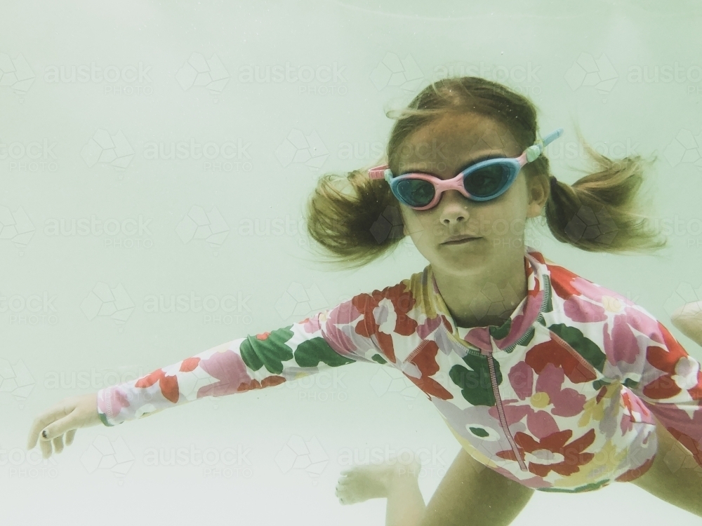 Image of Young girls swimming underwater in pool wearing floral ...