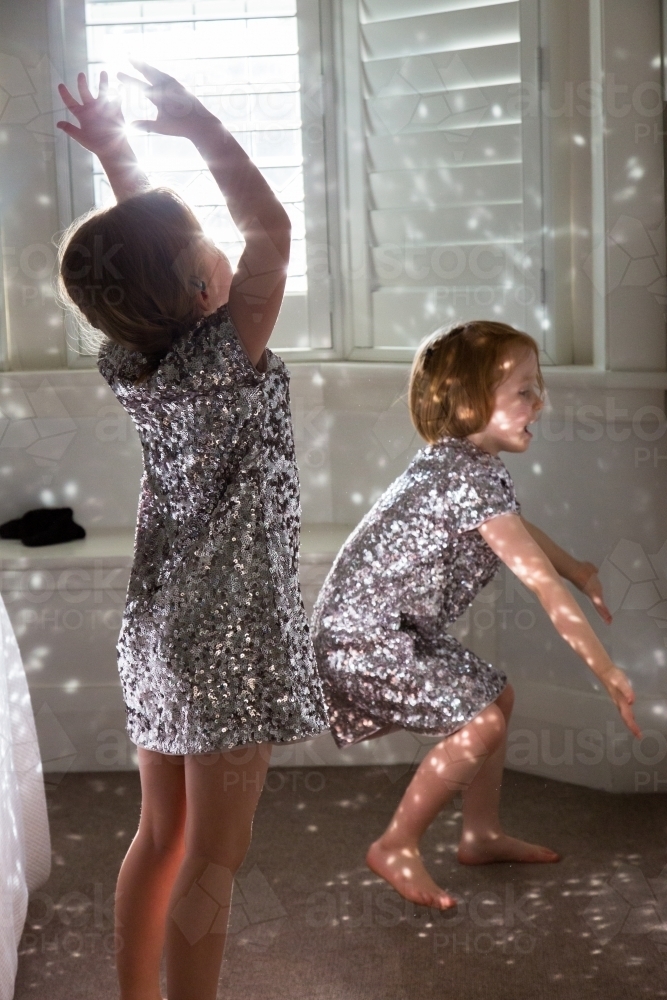 Image of Young girls wearing sparkly dresses playing with the reflected ...