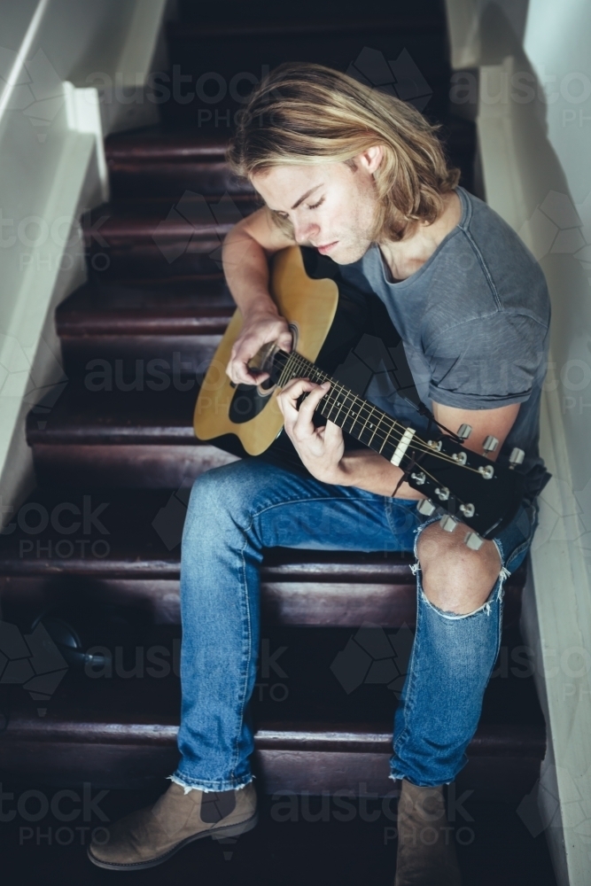 Image of Young guy playing guitar alone with a serious facial ...