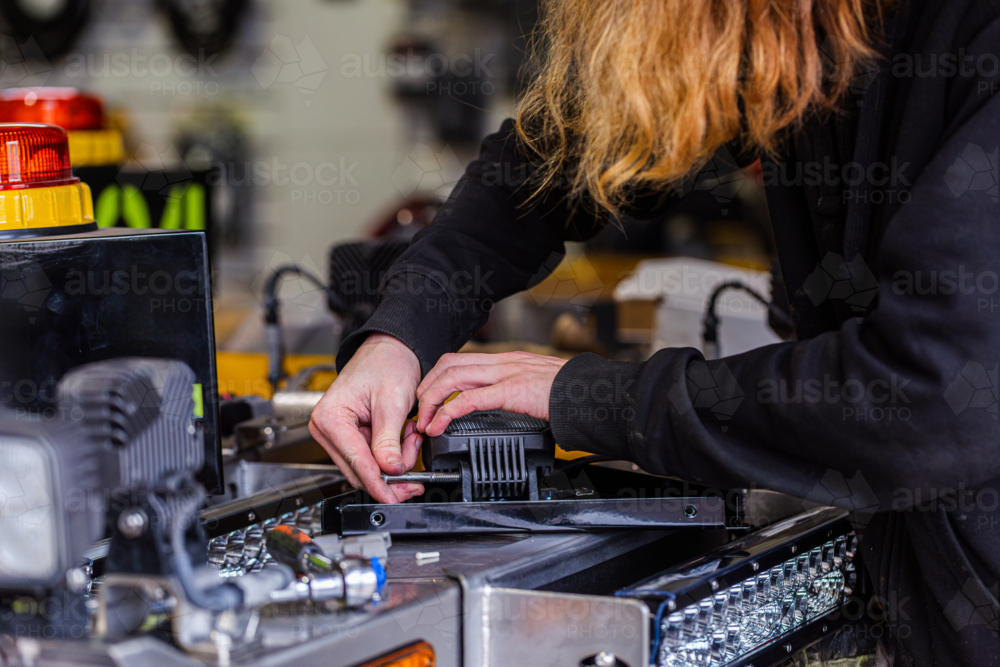 Image of Young male mechanic assembling light bar component in ...