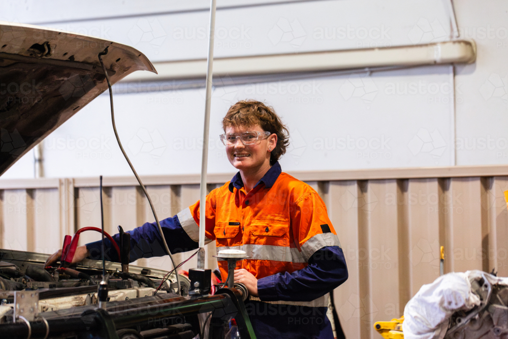 Image of Young male mechanic working on white vehicle with bonnet ...