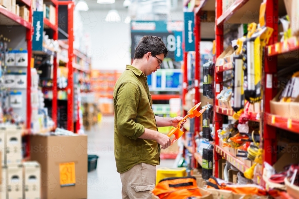 Image of Young man browsing in hardware store - Austockphoto