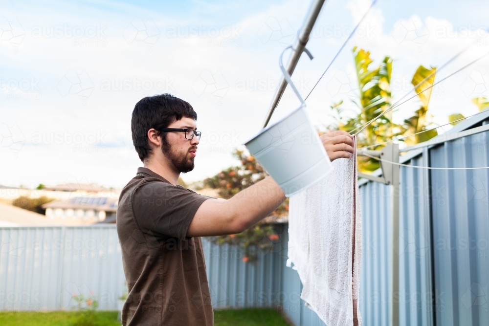 Image of Young man in backyard getting in washing off clothesline ...