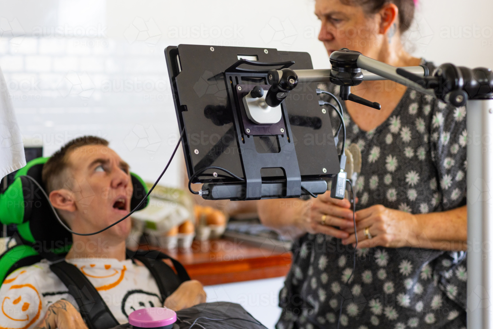Image of Young man with disability on his wheelchair looking at his mum ...