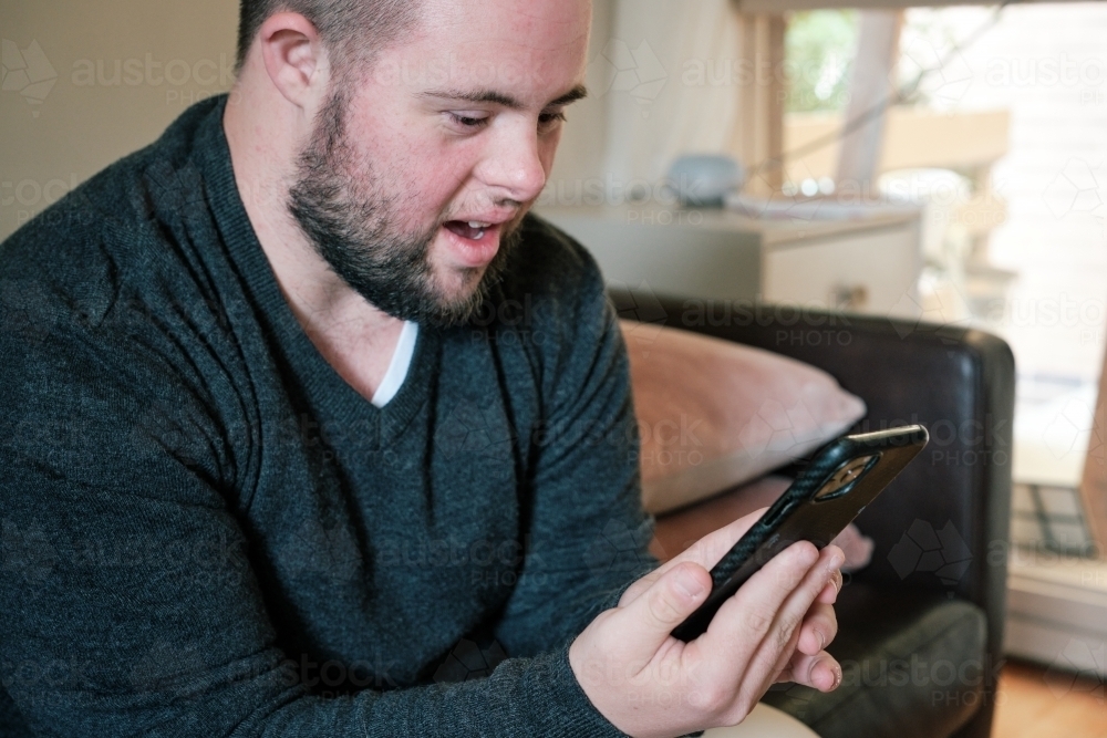 Image of Young Man with Down Syndrome holding Mobile Phone - Austockphoto