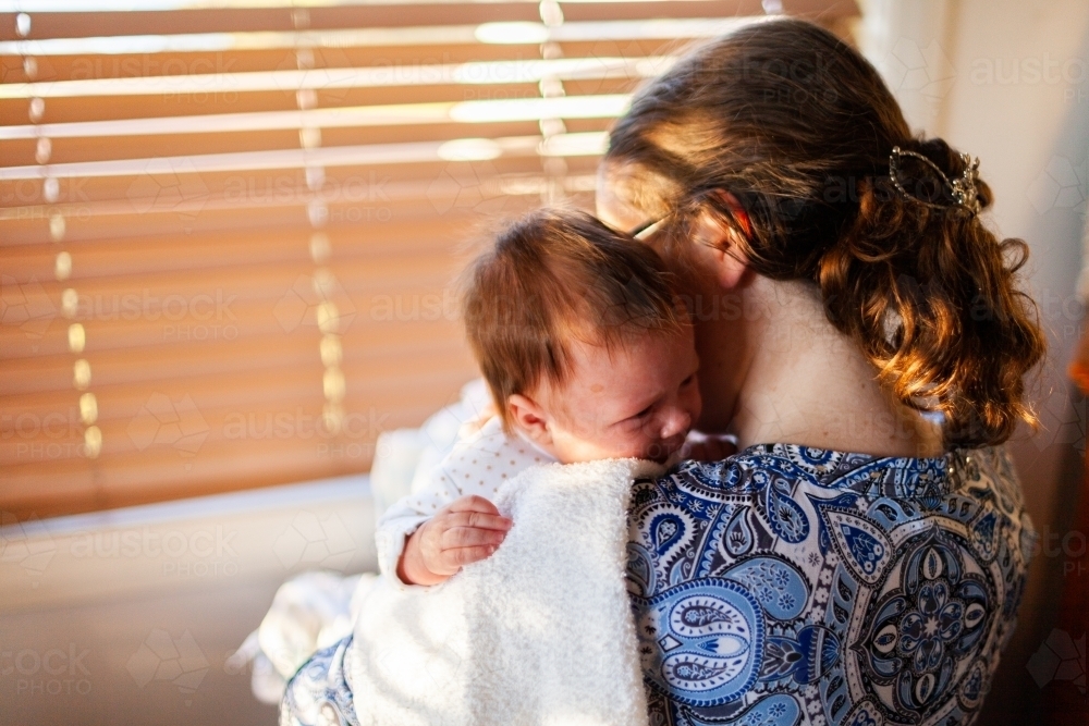 Image of Young mother comforting sad crying baby child - Austockphoto