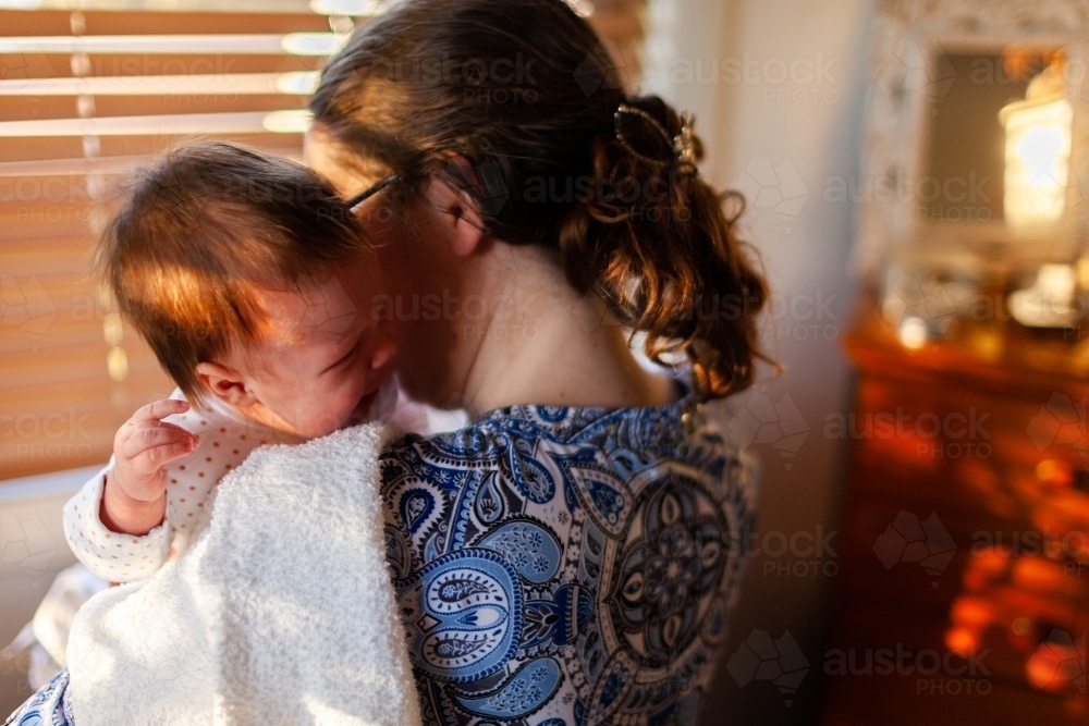 Image of Young mother comforting sad crying baby child - Austockphoto