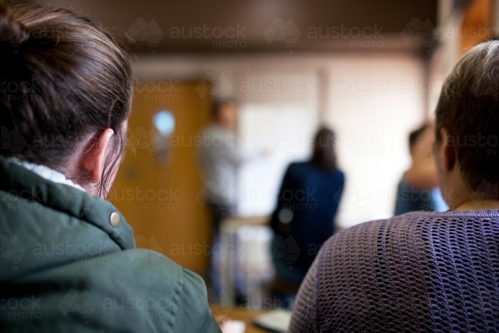 Image of Young people from behind sitting in a classroom - Austockphoto