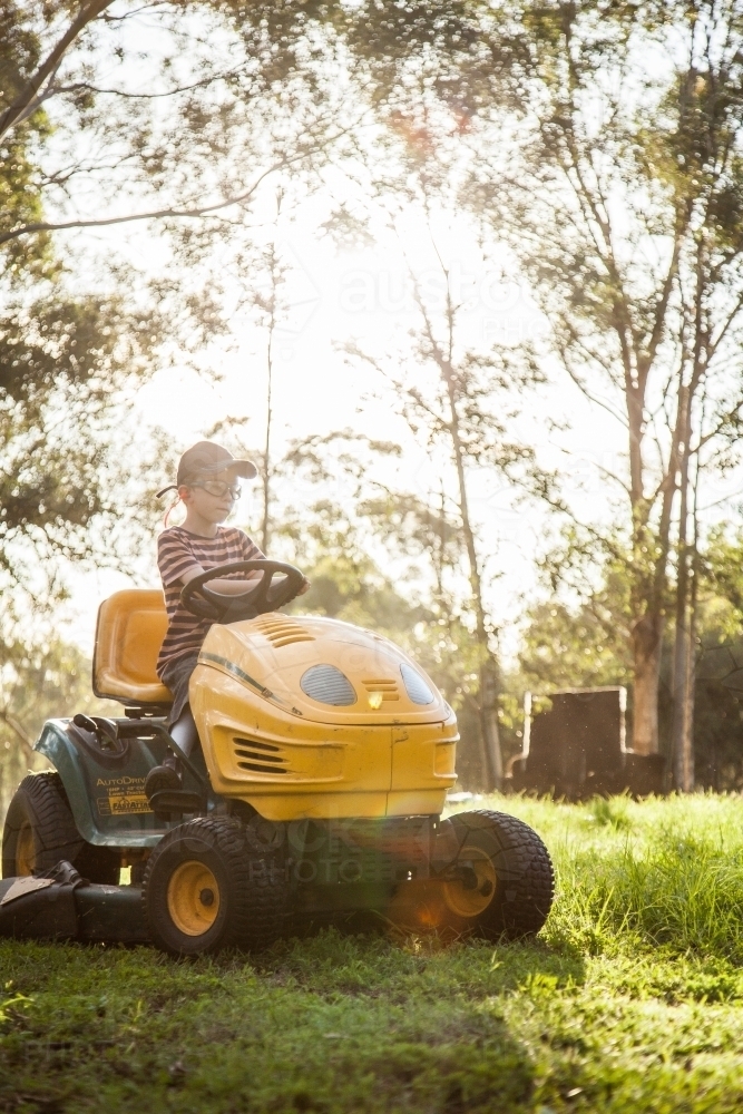 Image of Young person mowing the paddock on a ride on lawn mower in ...