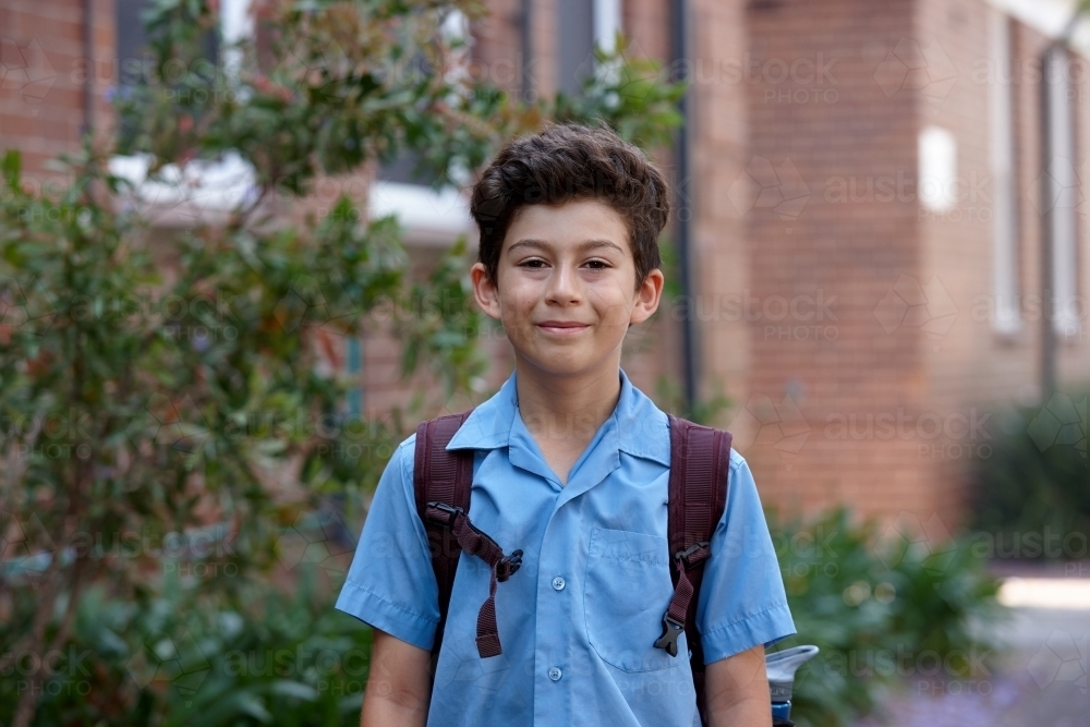 Image of Young school boy at school with backpack - Austockphoto