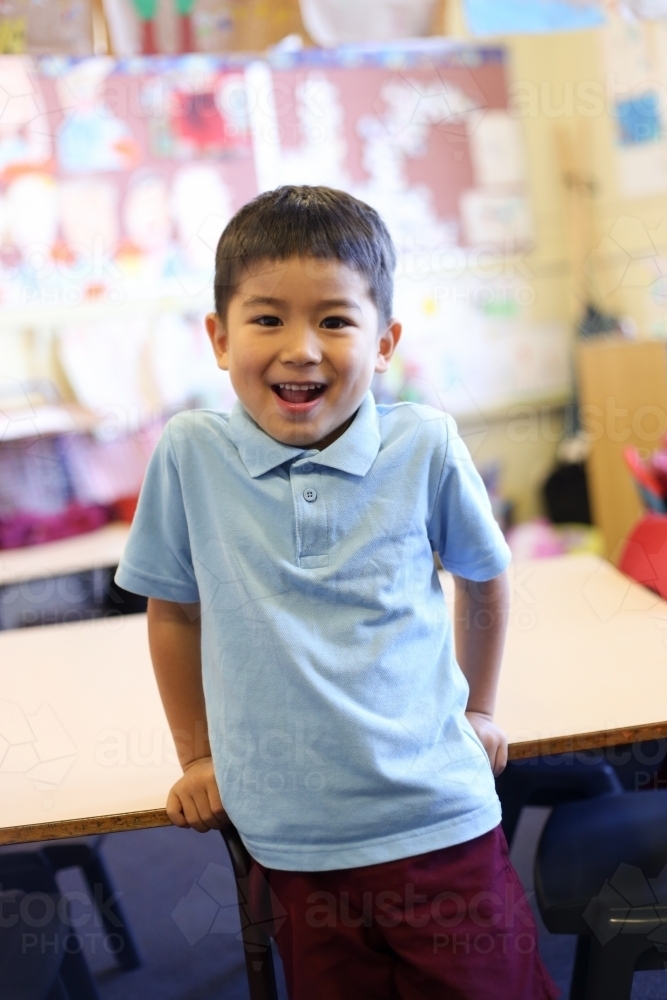 Image of Young school boy standing in classroom - Austockphoto