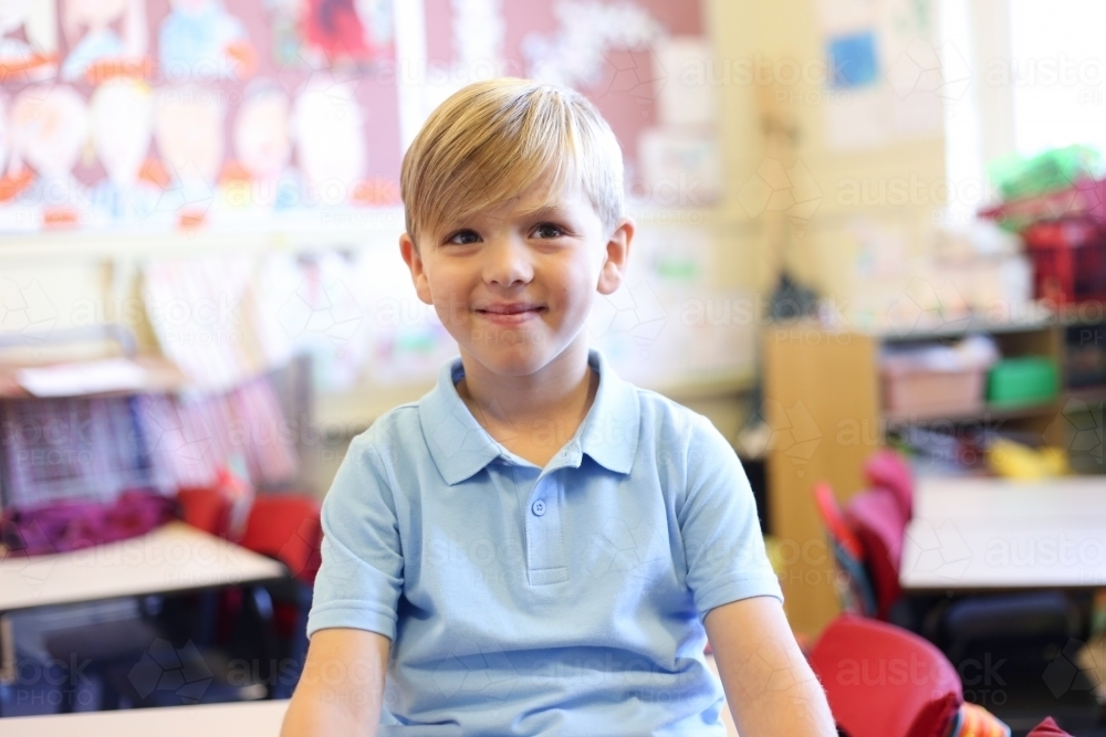 Image of Young smiling boy sitting in classroom - Austockphoto
