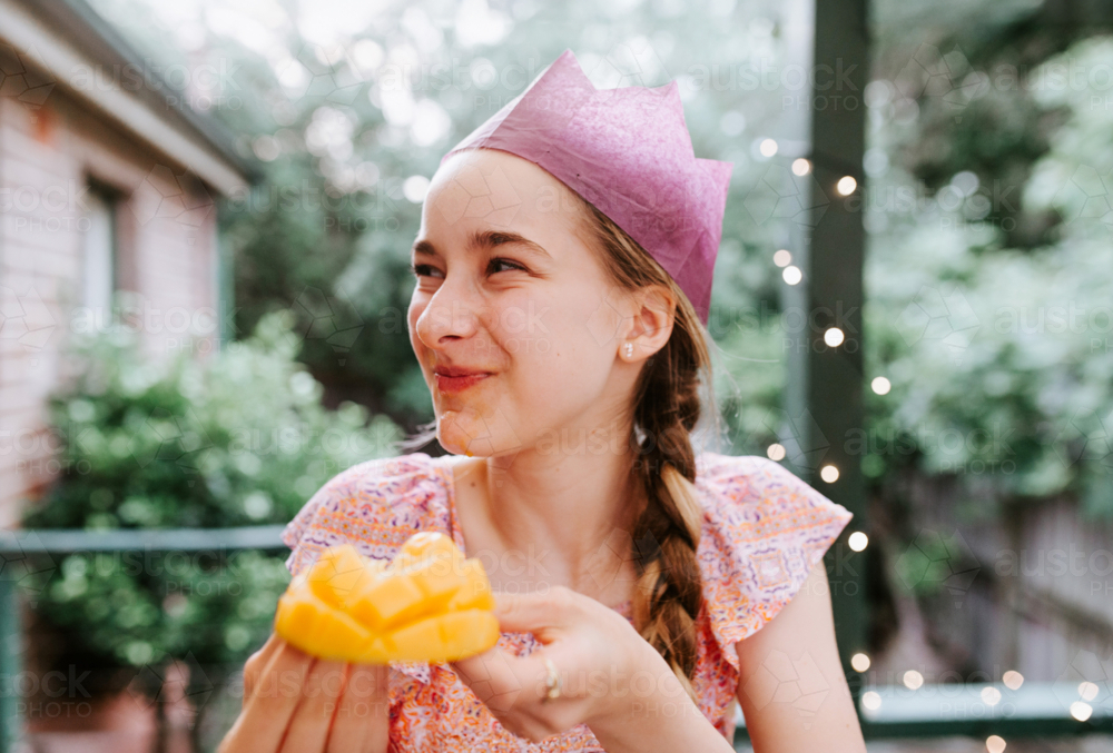 Image of Young teenage girl enjoying a fresh ripe mango. - Austockphoto