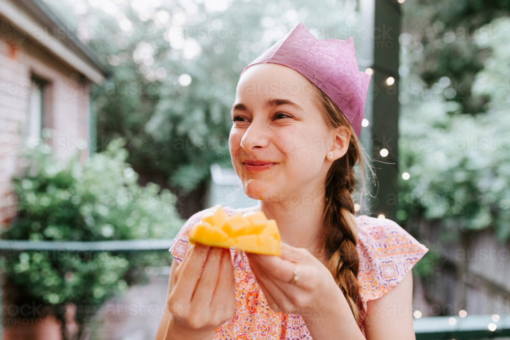 Image of Young teenage girl enjoying a fresh ripe mango. - Austockphoto