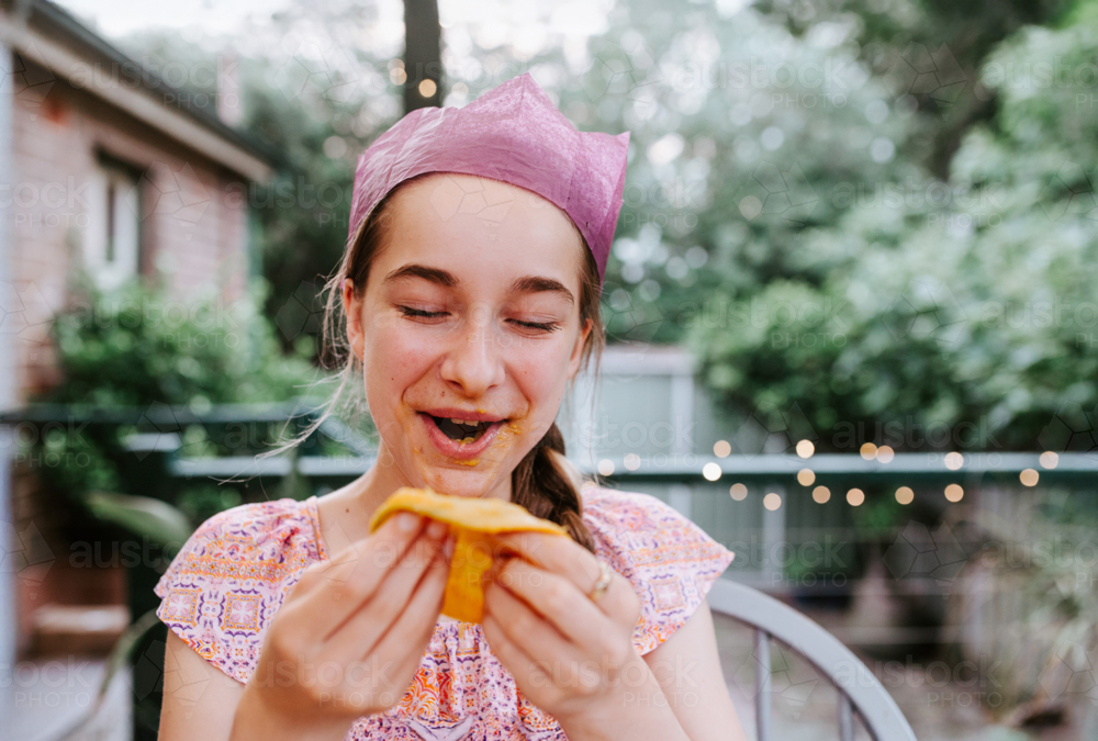 Image of Young teenage girl enjoying a fresh ripe mango. - Austockphoto