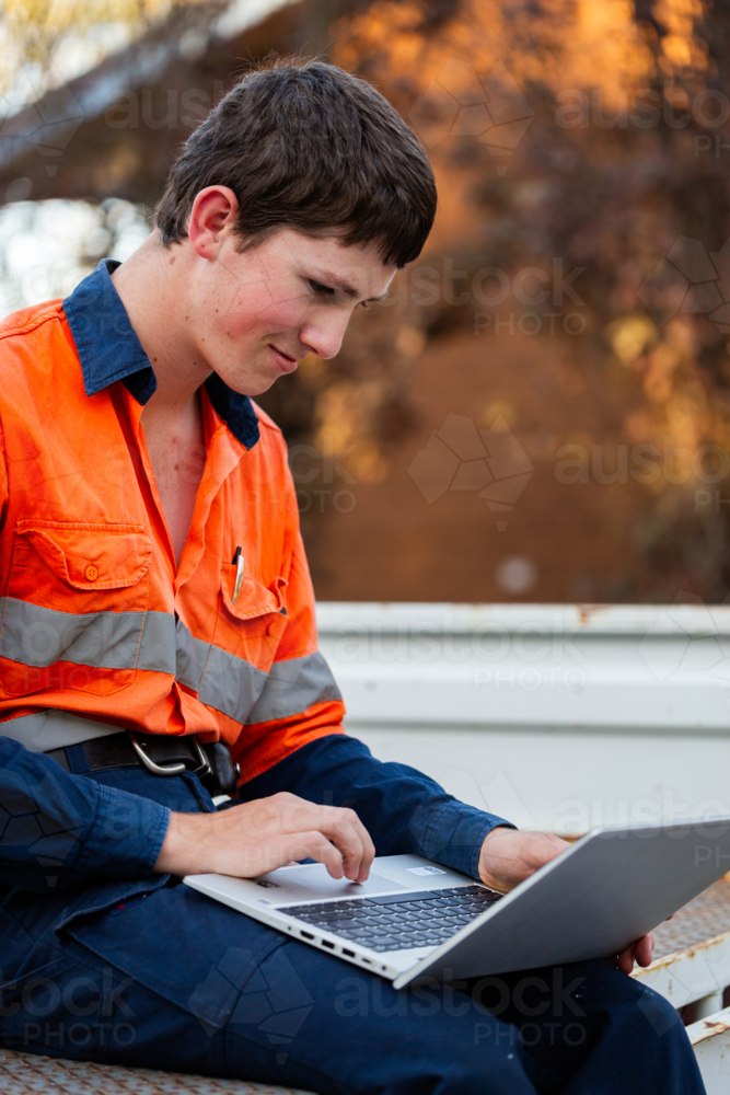 Image of Young teenaged trainee tradie apprentice working on laptop in ...