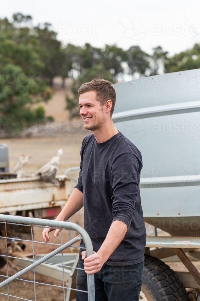 Image of Young tourist opening a gate on a farm - Austockphoto