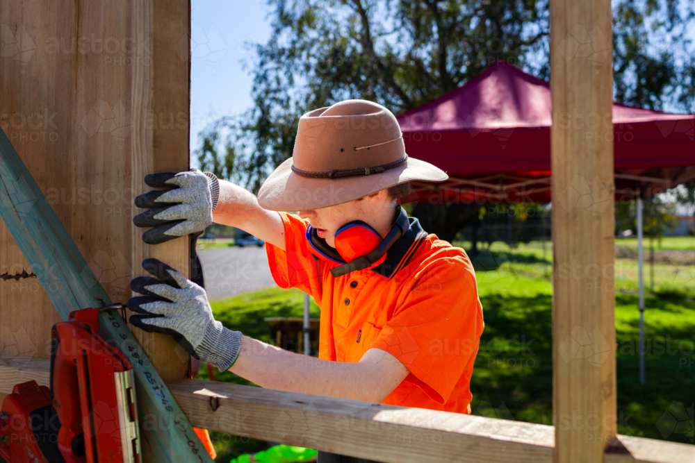 Image of Young trainee apprentice worker with gloves holding wood to ...