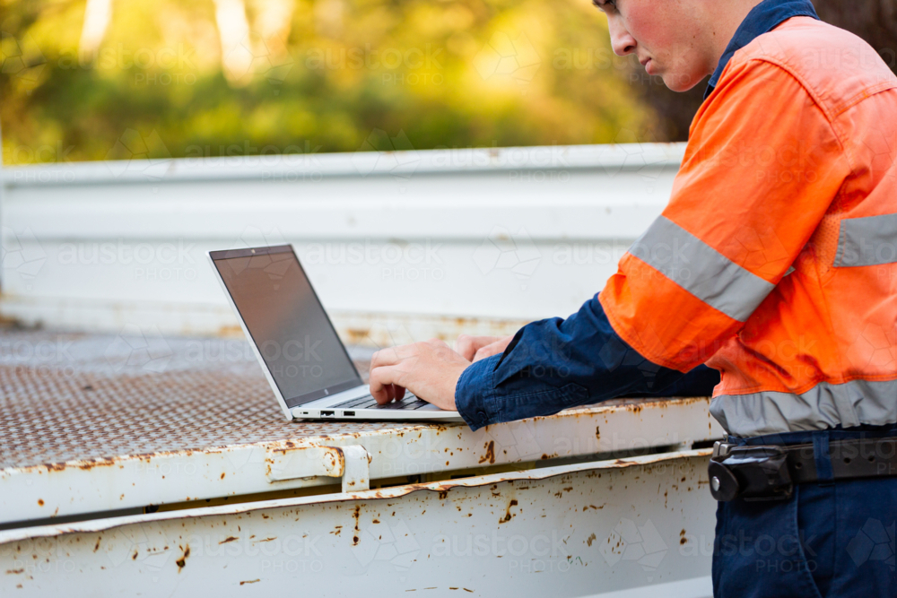 Image of Young trainee tradie apprentice working on laptop in back of ...