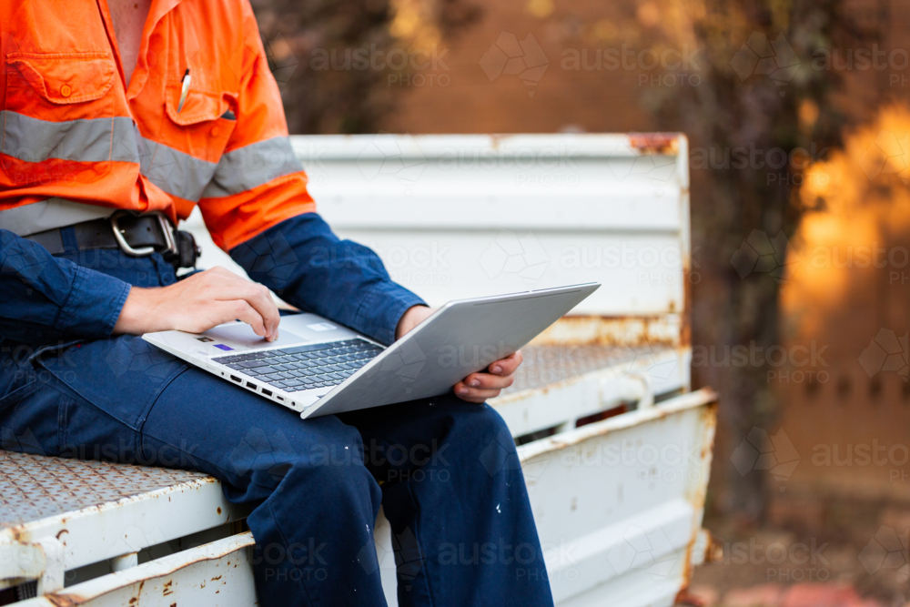 Image of Young trainee tradie apprentice working on laptop in back of ...
