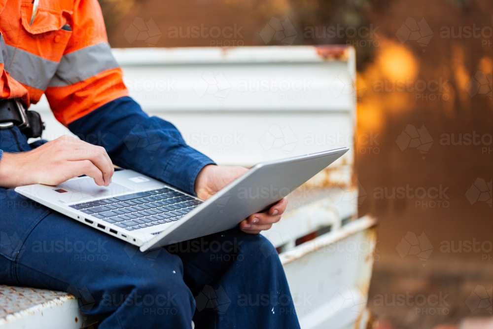Image of Young trainee tradie apprentice working on laptop in back of ...