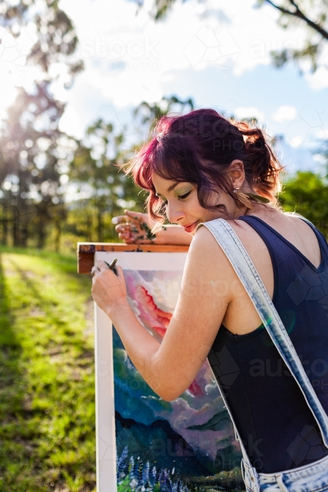 Image of Young woman artist working on painting in afternoon light ...
