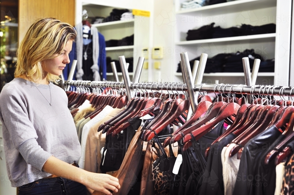 Image of young woman browsing in a clothing boutique - Austockphoto