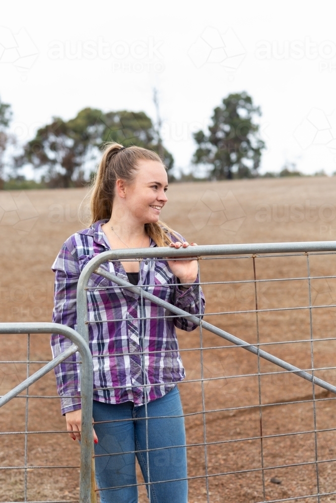 Image of Young woman closing farm gate - Austockphoto
