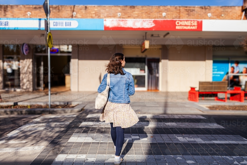 Image of Young woman crossing road on pedestrian crossing in country ...