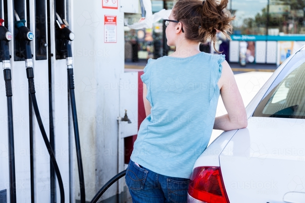 Image of Young woman filling up her car with petrol at the servo ...