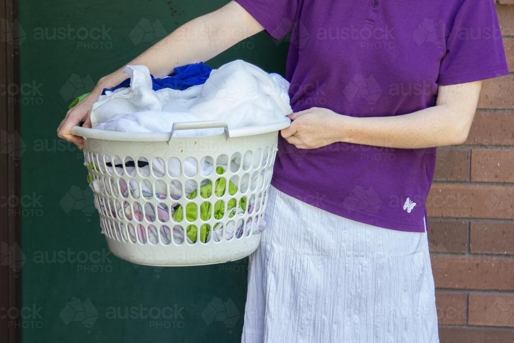Image of Young woman holding a basket of wet washing - Austockphoto