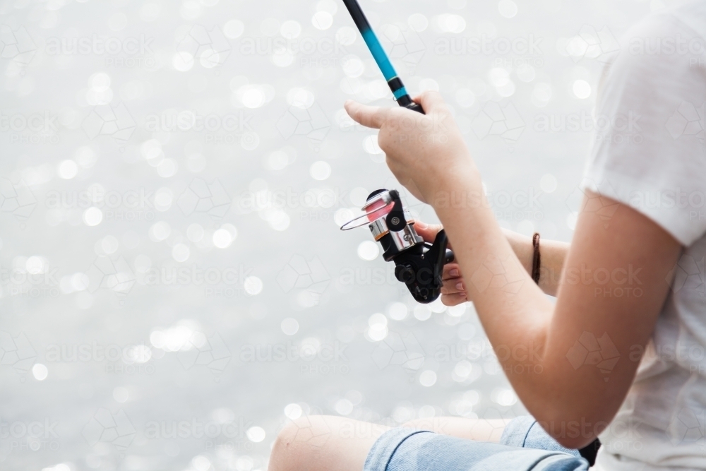 Image of Young woman holding a fishing rod with out of focus water ...