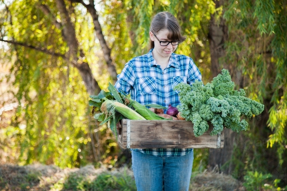 Image of Young woman in flannel shirt smiling and holding crate of ...