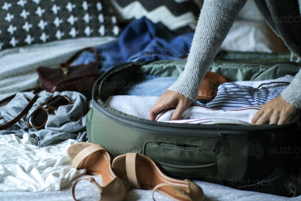 Image of Young woman packing her bag ready to travel - Austockphoto
