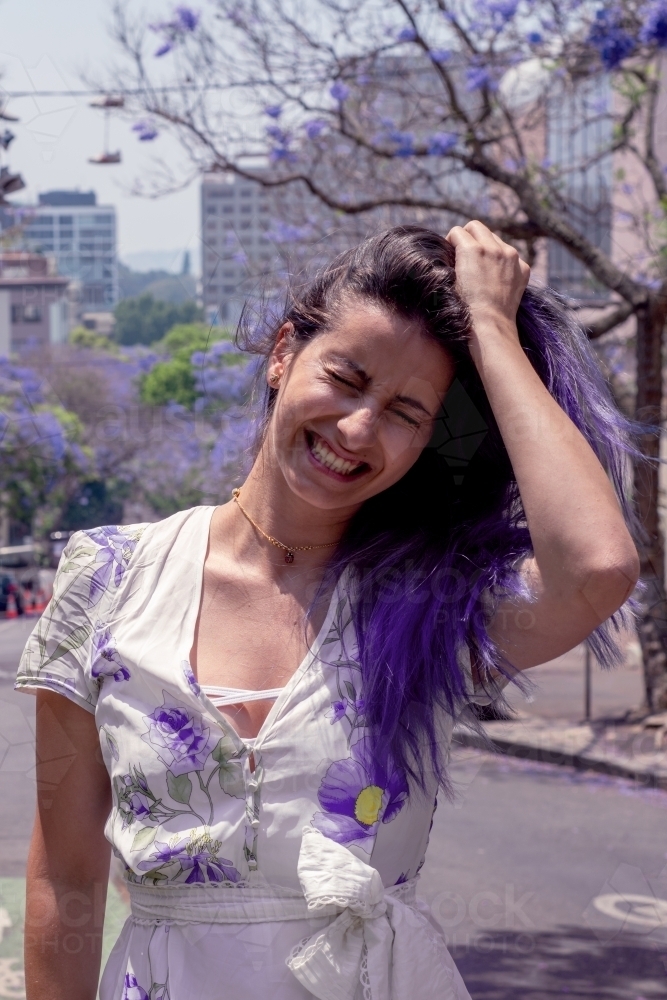 Image of young woman posing under jacaranda tree - Austockphoto