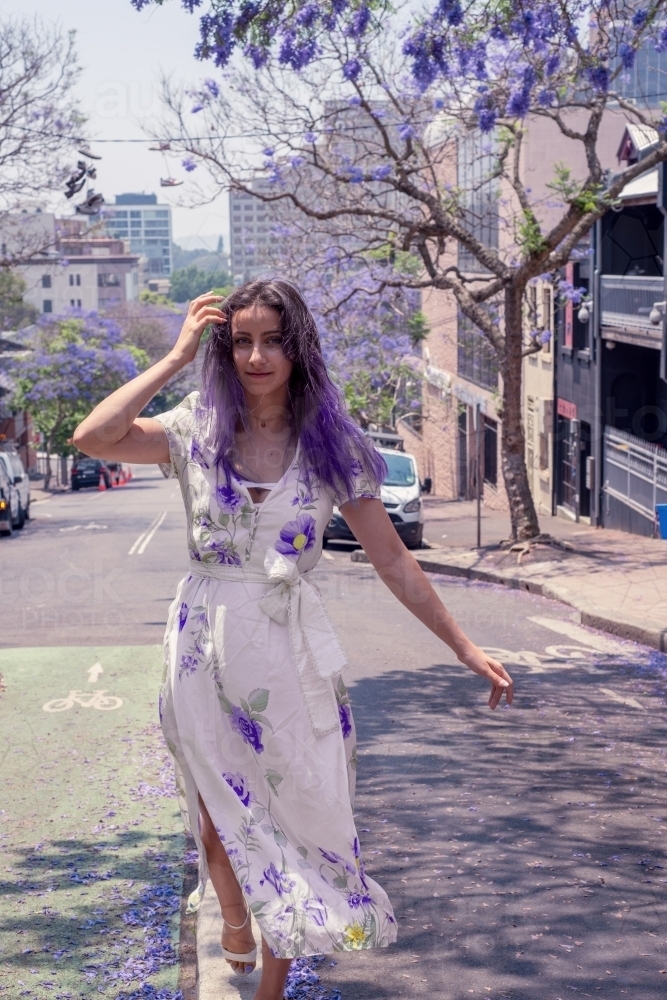 Image of young woman posing under jacaranda tree - Austockphoto