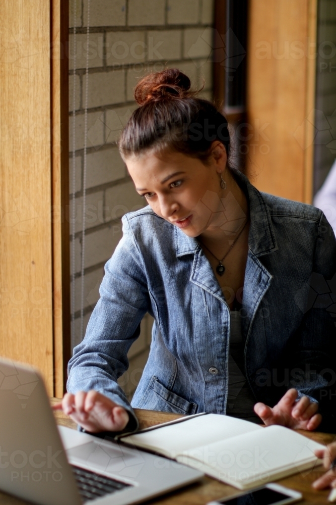 Image of Young woman sitting at desk studying with books and laptop ...