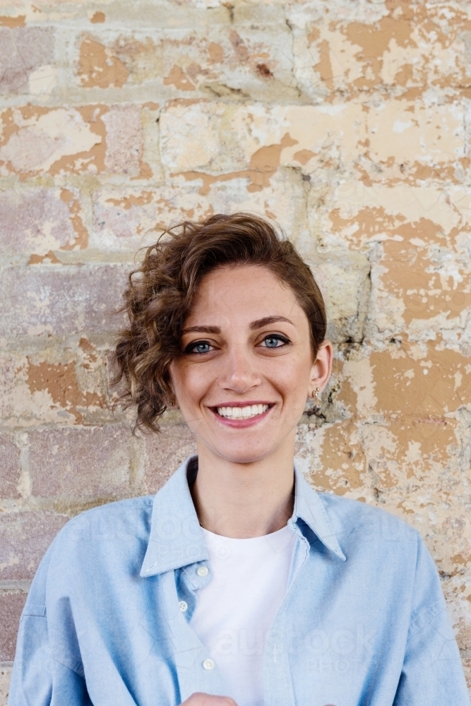 Image of young woman standing against brick wall - Austockphoto