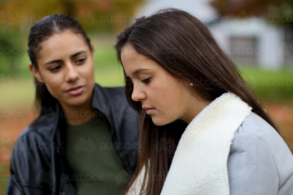 Image of Young woman with upset expression being comforted by female ...