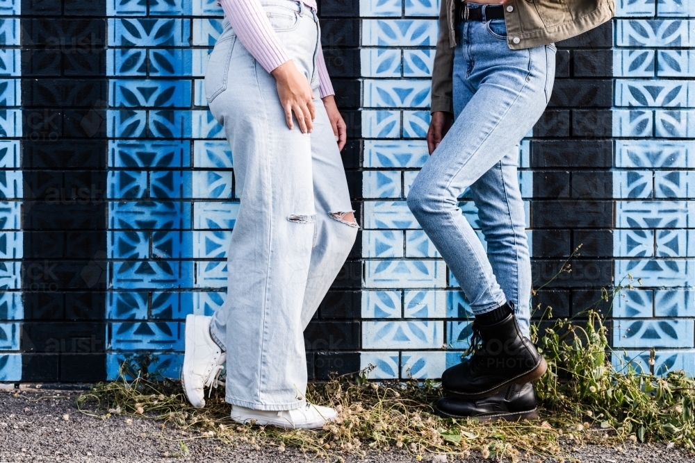 Image of young women standing against a wall, legs only - Austockphoto