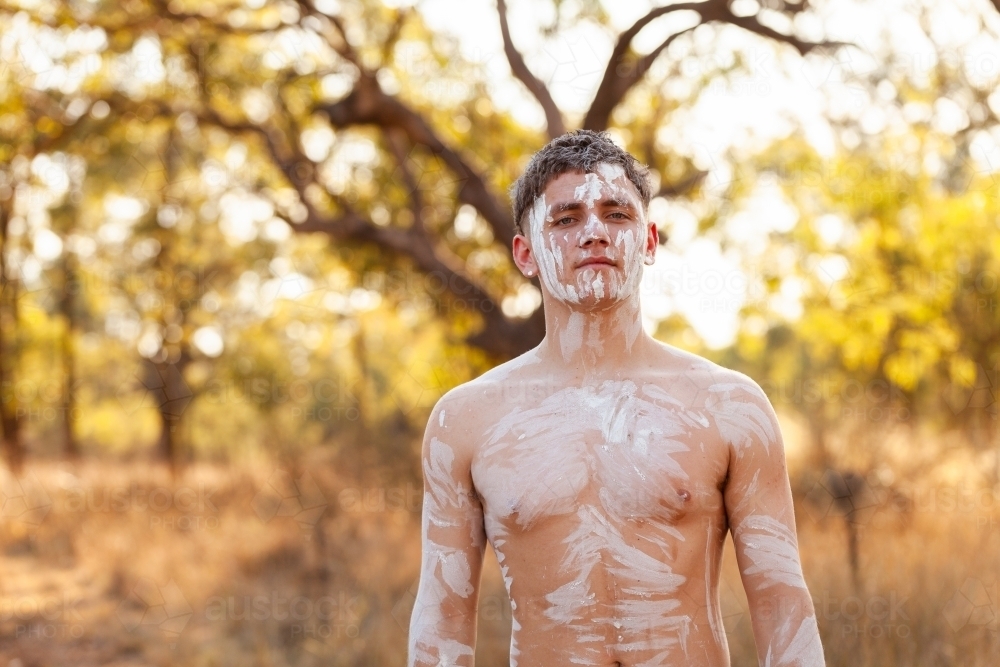 Image of Young Wonnarua man with serious expression and bokeh bushland ...